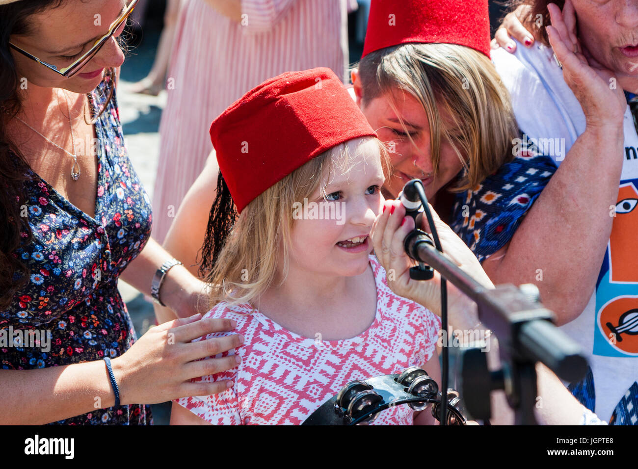 Close up of Caucasian blonde child, girl, standing with other people ...
