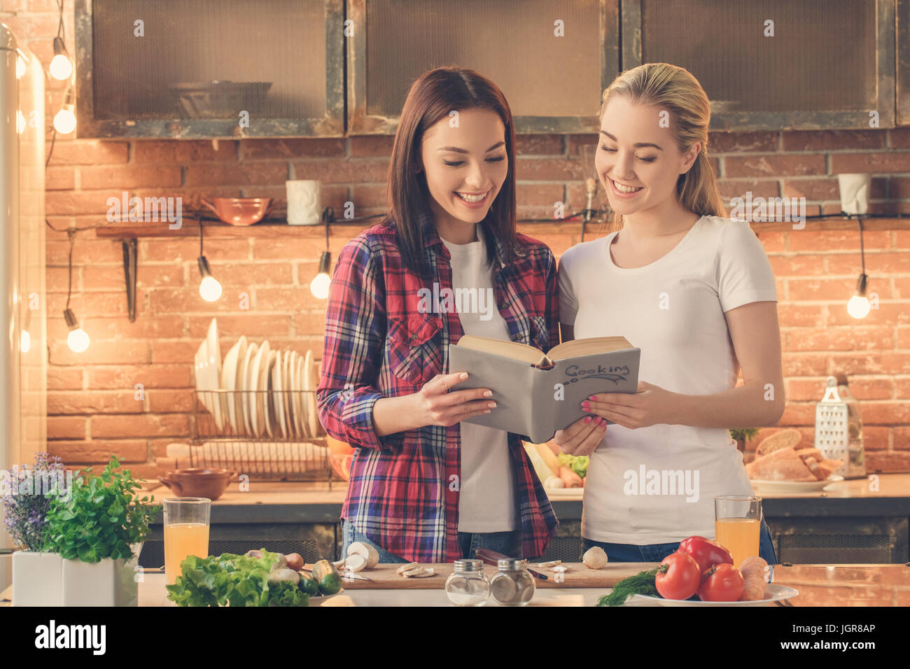 Young women friends cooking meal together at home Stock Photo - Alamy