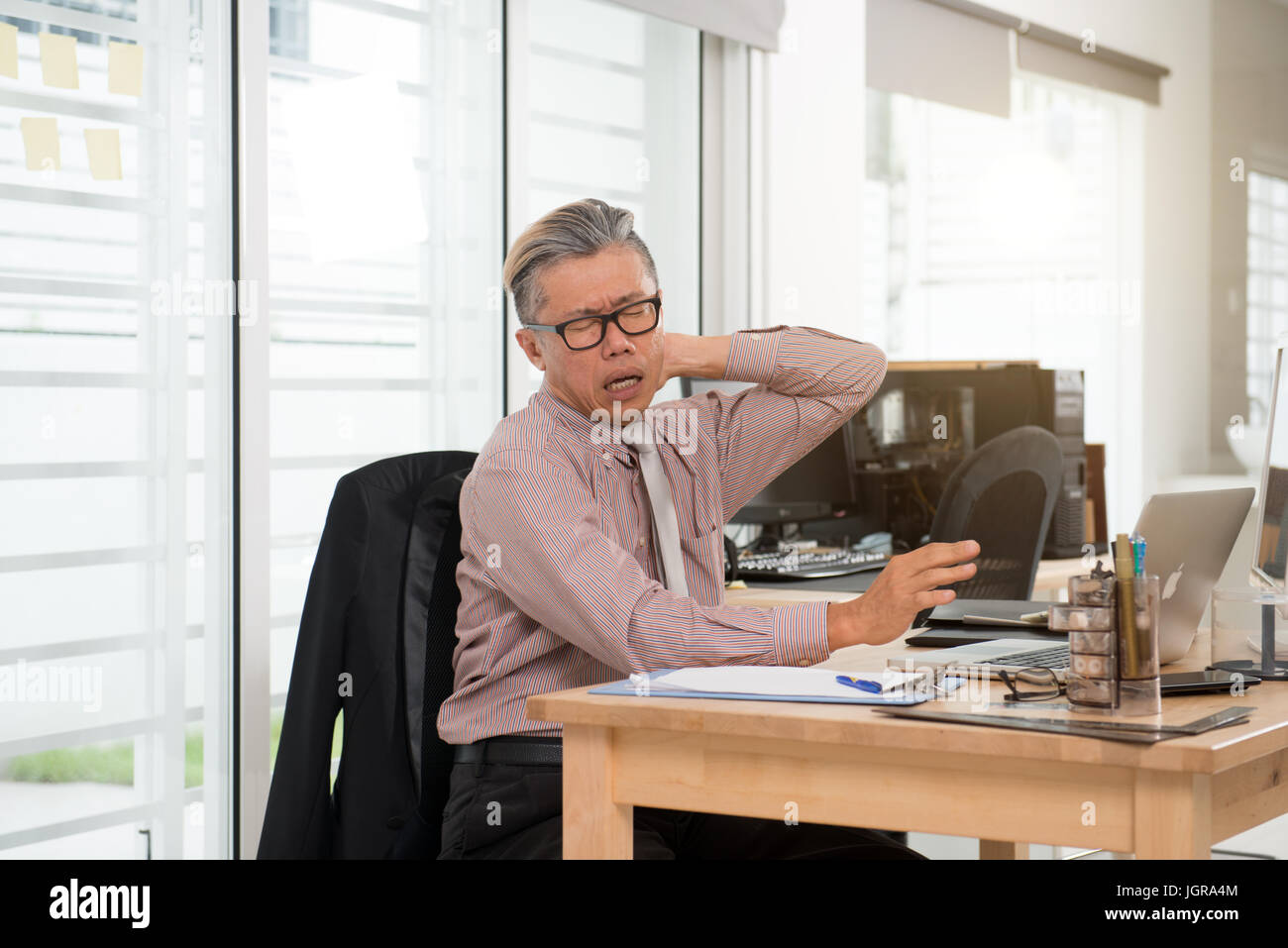asian business senior male neck pain at work place Stock Photo - Alamy