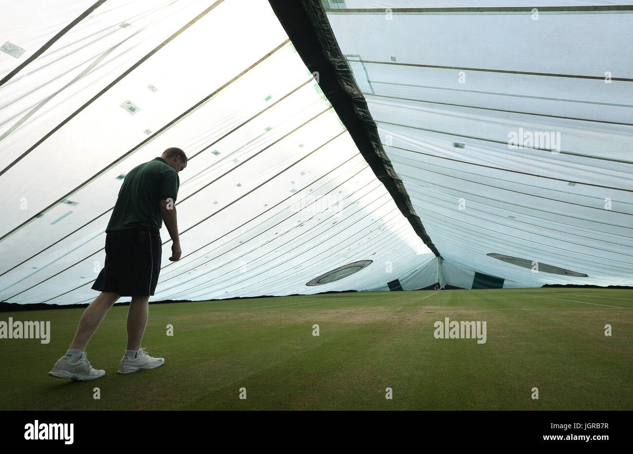 A member of ground staff checks the grass under the covers on centre ...
