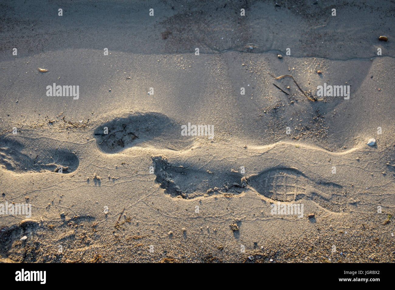 Beach side with wet footsteps after the beach guests Stock Photo - Alamy