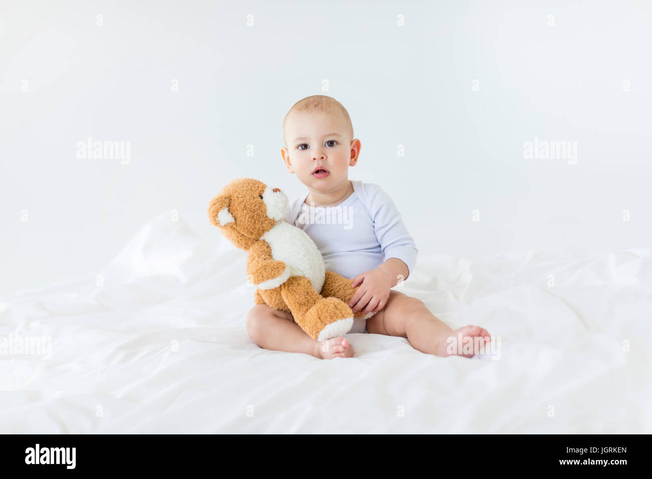 Portrait of adorable small baby boy with teddy bear playing on bed, 1 ...