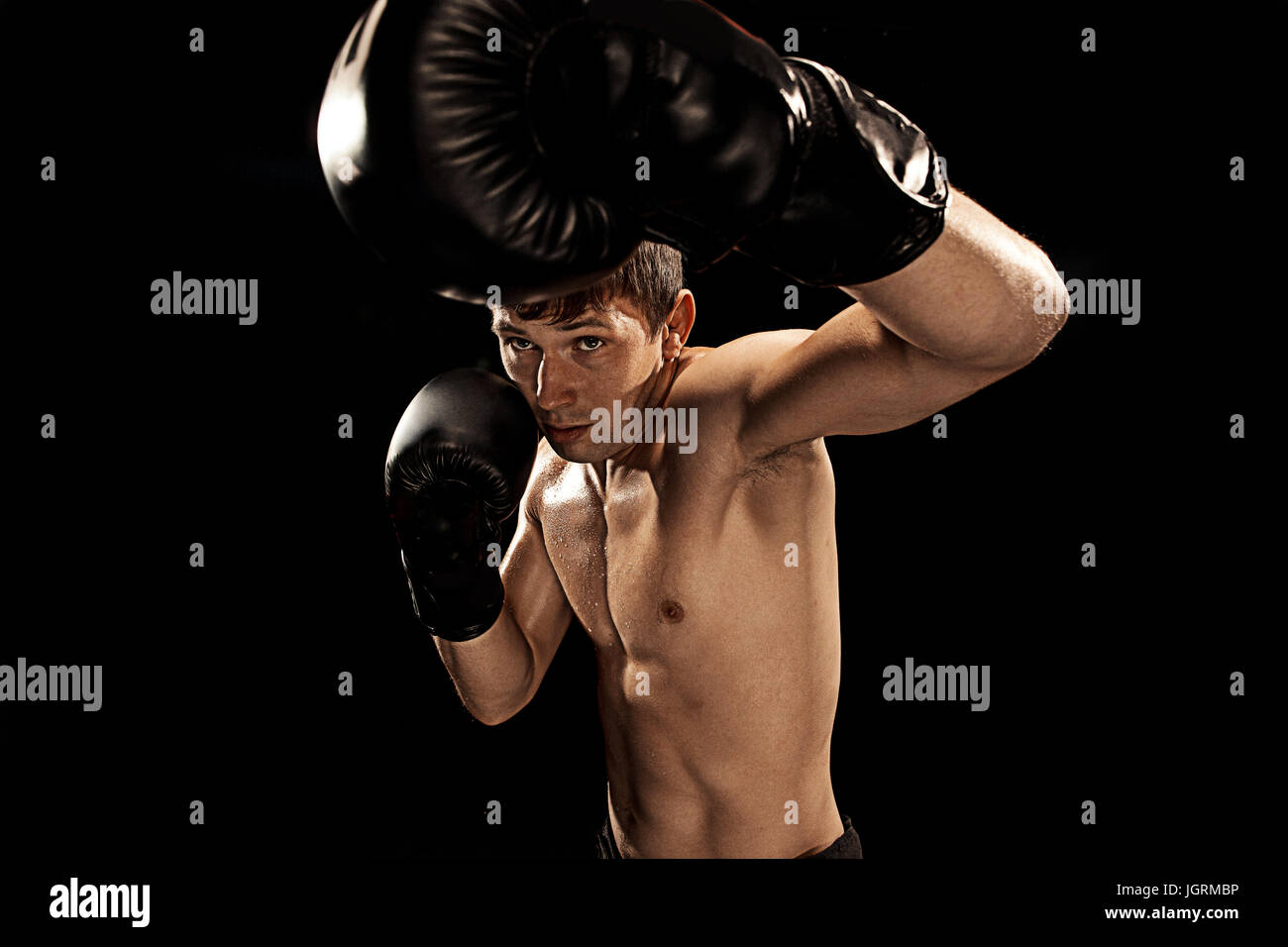 Male boxer boxing in punching bag with dramatic edgy lighting in a dark ...