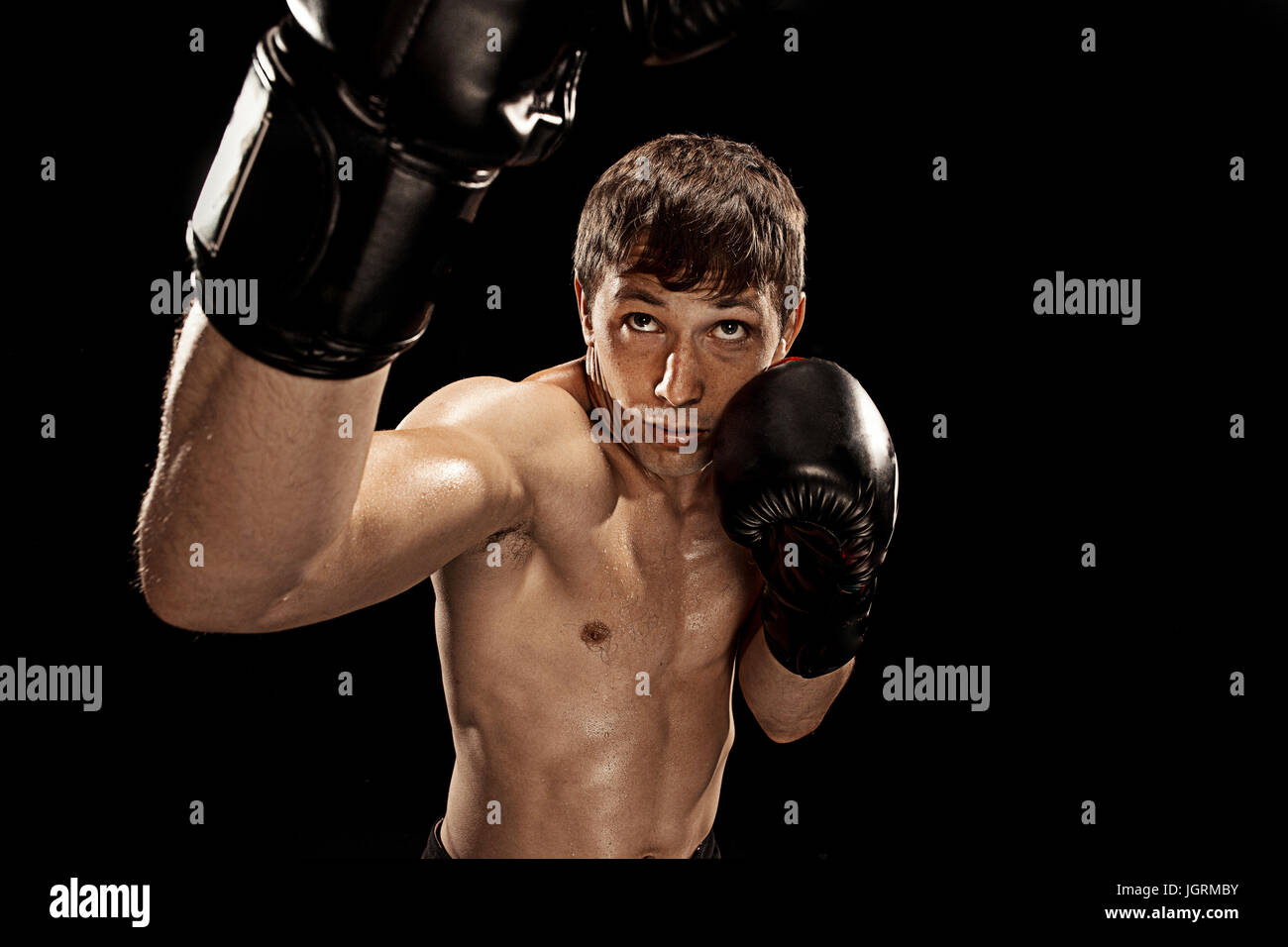 Male boxer boxing in punching bag with dramatic edgy lighting in a dark ...