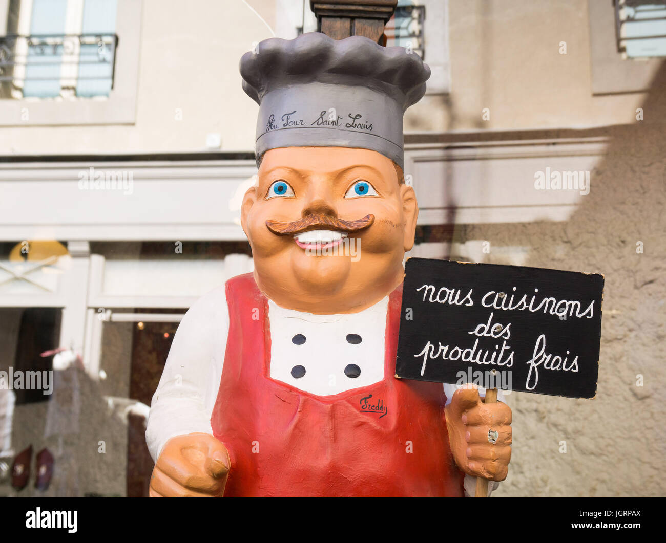 A figure outside a French restaurant with a sign saying "Nous cuisinons ...