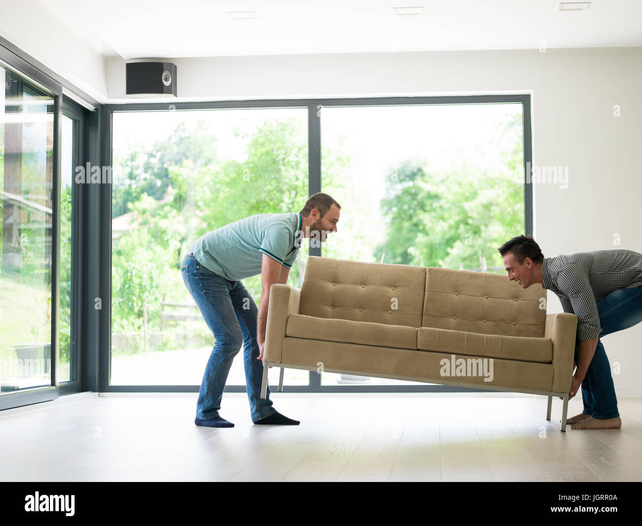 two young men carry the sofa in front of window Stock Photo - Alamy