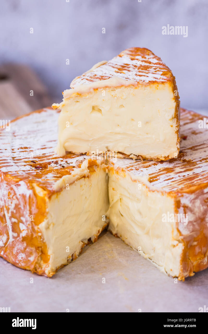 Wheel of soft camembert cheese with cut off piece on top, wood cutting ...