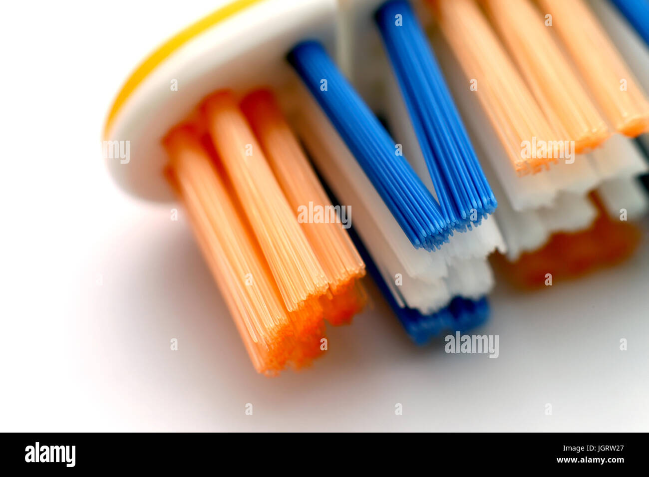 New toothbrush with yellow, blue and white bristles on the plastic base ...
