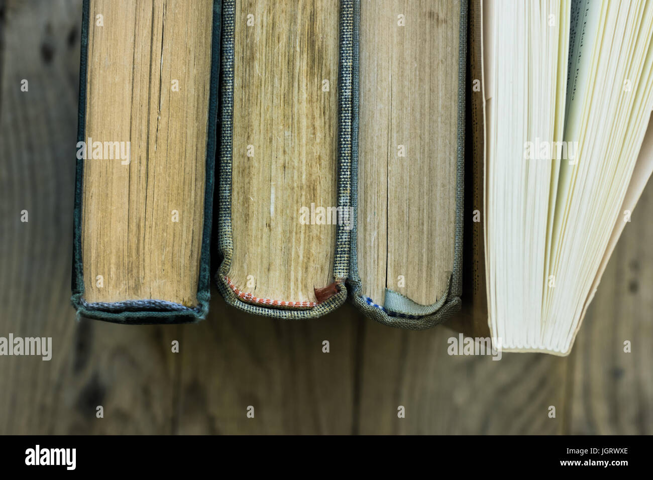 Row of old and new books, top view of spine, weathered wood background ...