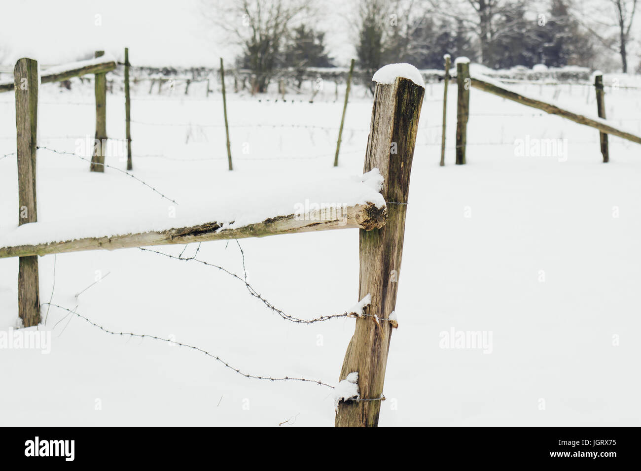 Closeup on a wooden fence covered in snow in a rural field during the ...