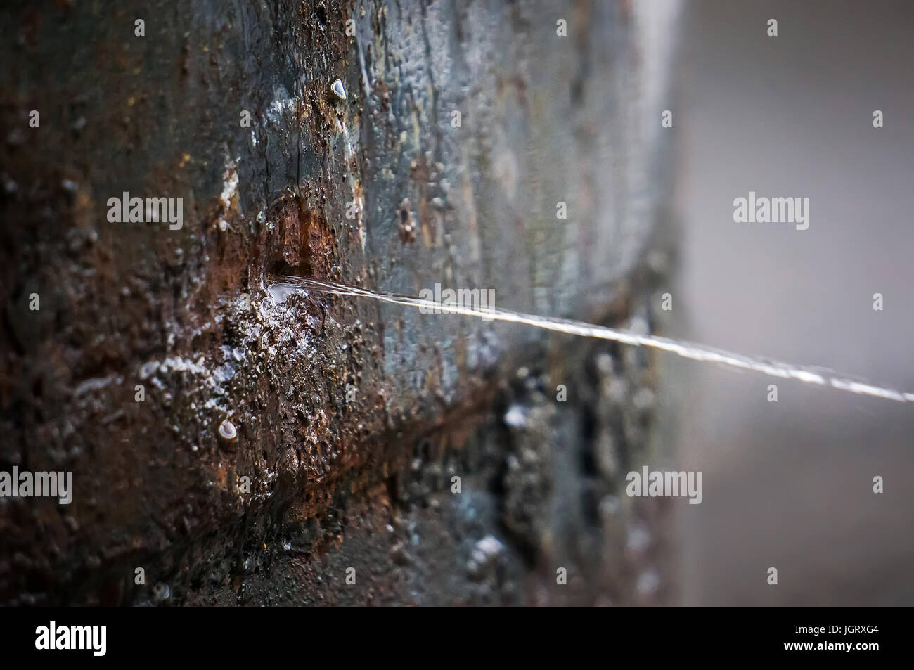 Rusty burst pipe spraying water after freezing in winter. Old worn ...