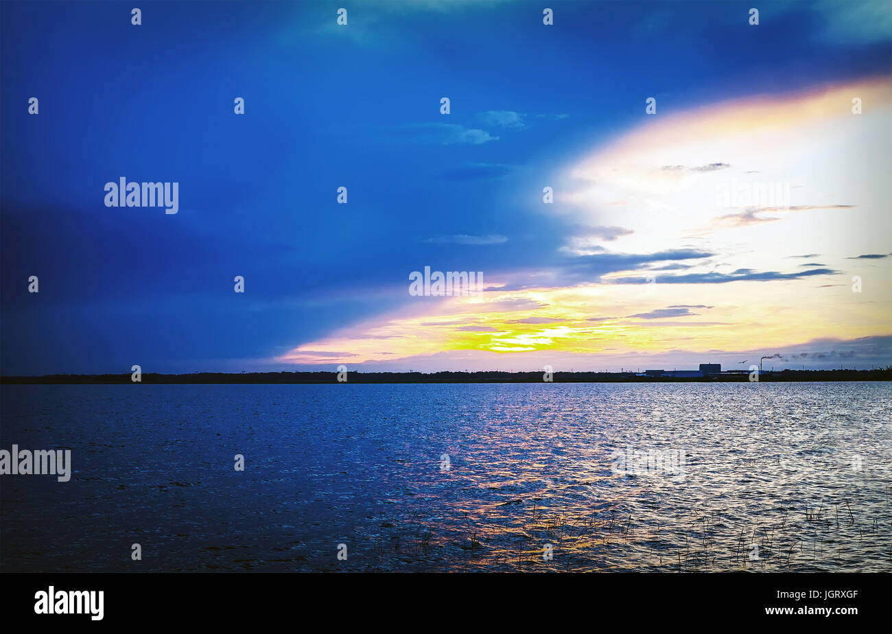 Bright blue and yellow sunset. The sun going beyond the horizon beyond ...
