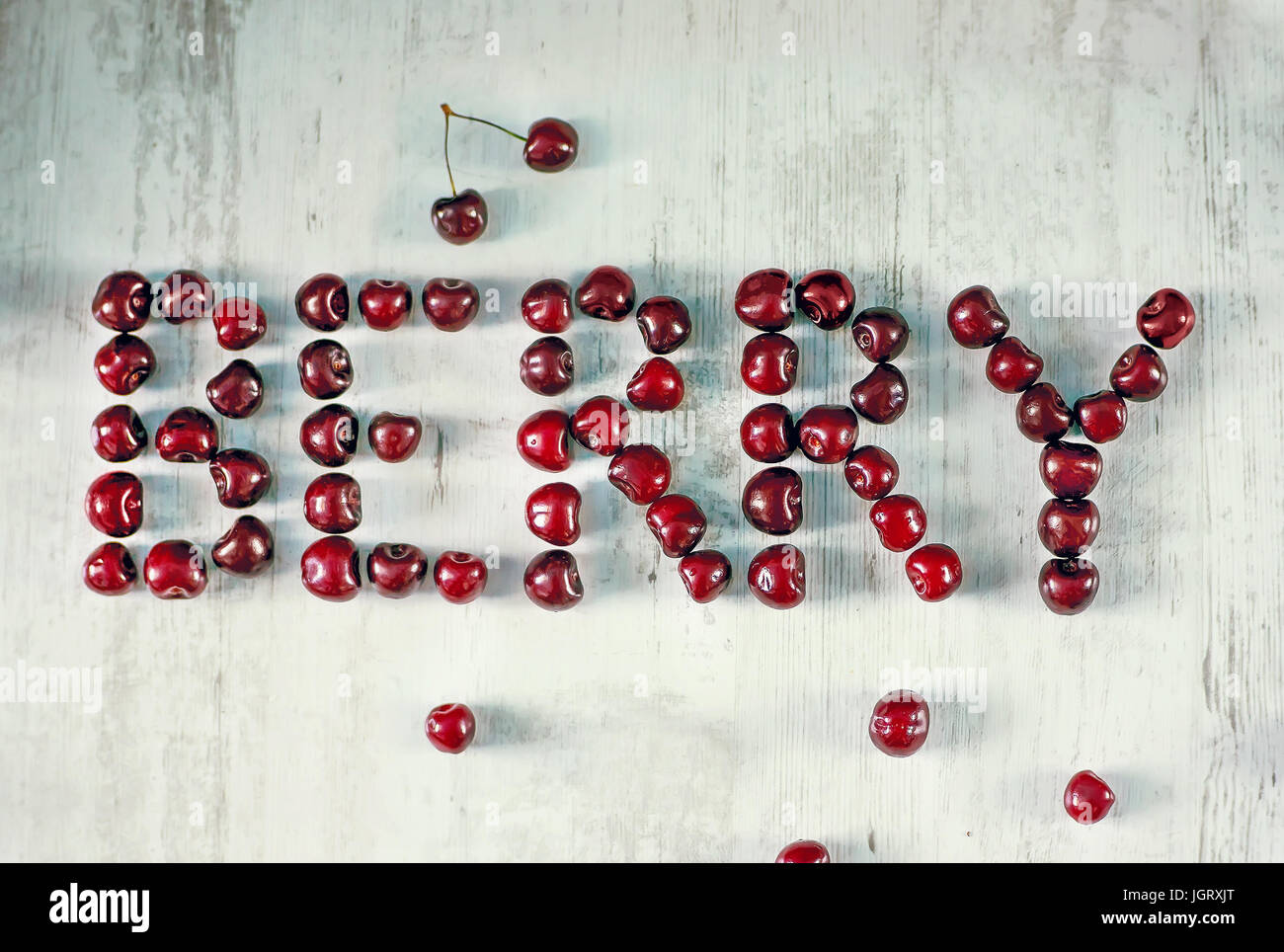 word berry is lined with berries ripe cherry on a white vintage wooden ...