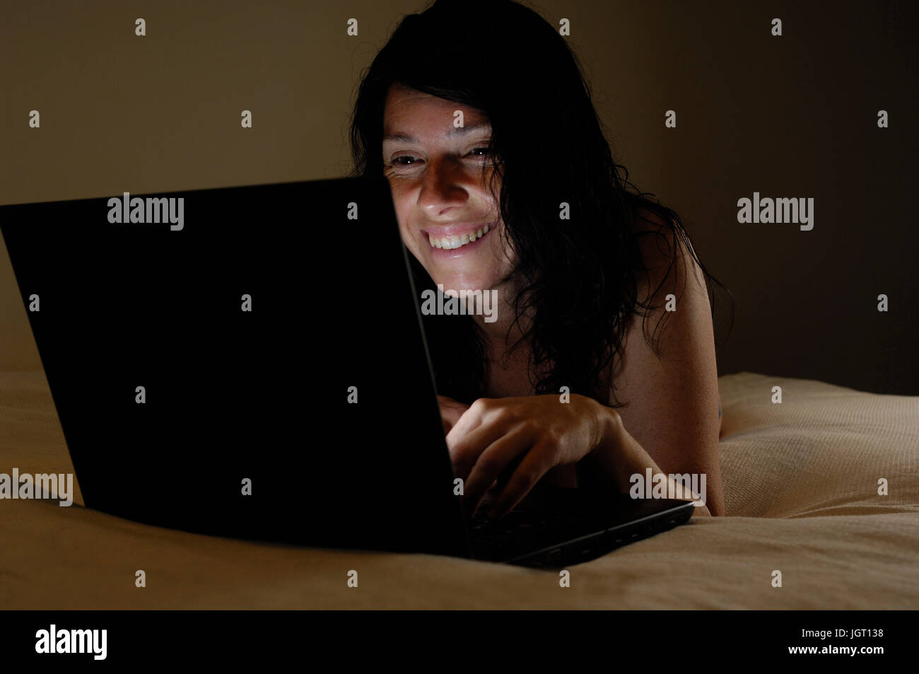 Woman with computer in bed Stock Photo - Alamy