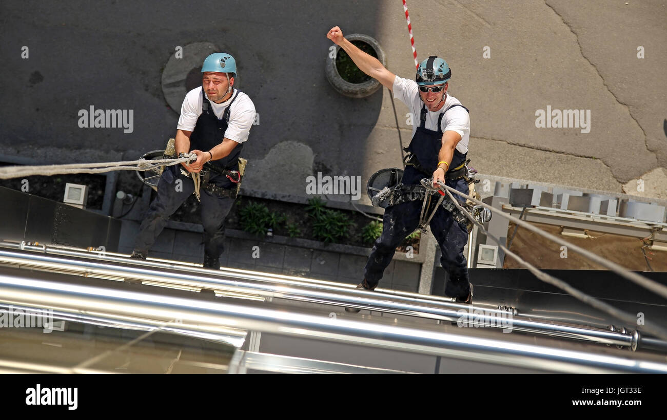 Workers hanging on climbing ropes, showing raised fist sign Stock Photo ...