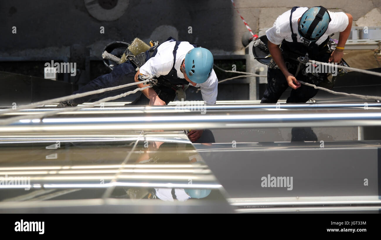 Workers hanging on climbing ropes and working together Stock Photo - Alamy