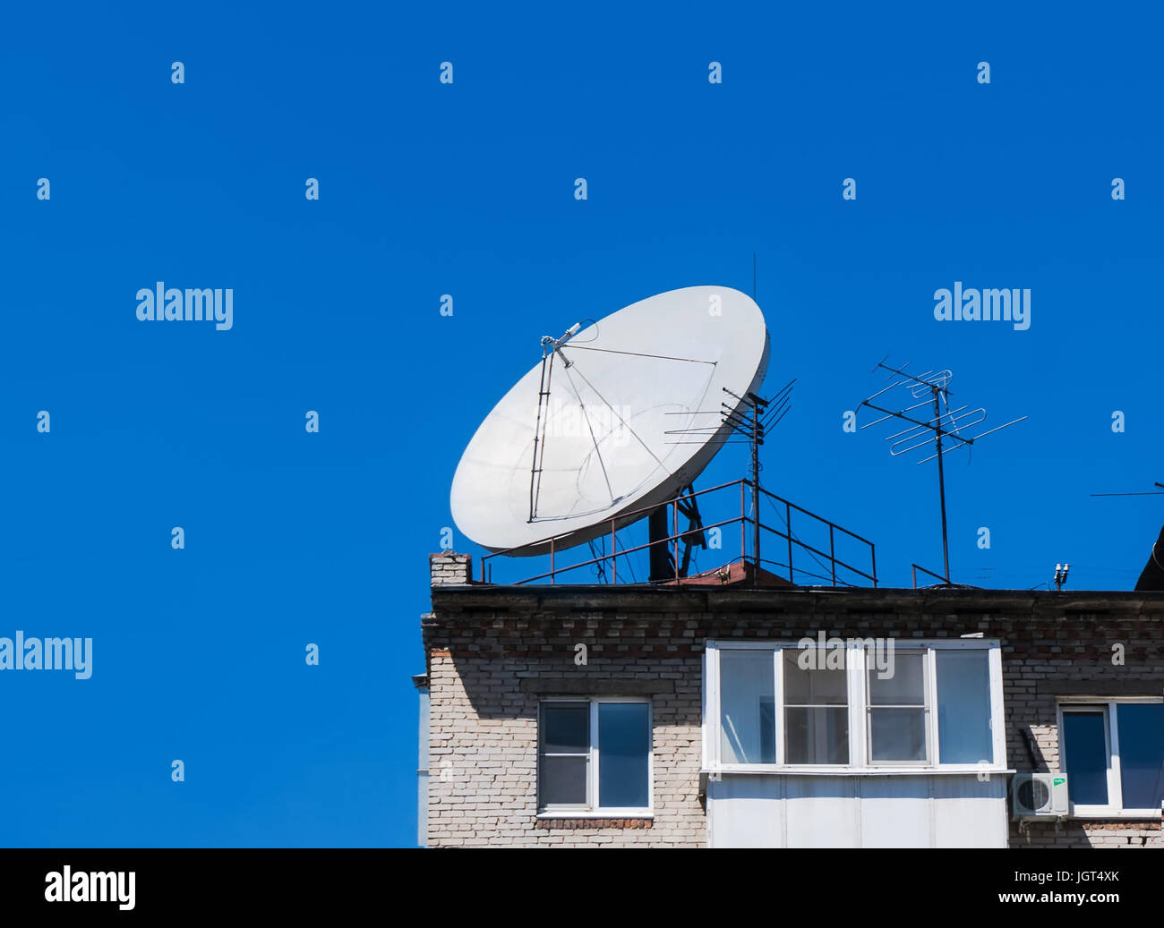 a huge satellite dish on the roof of a brick building in the background ...
