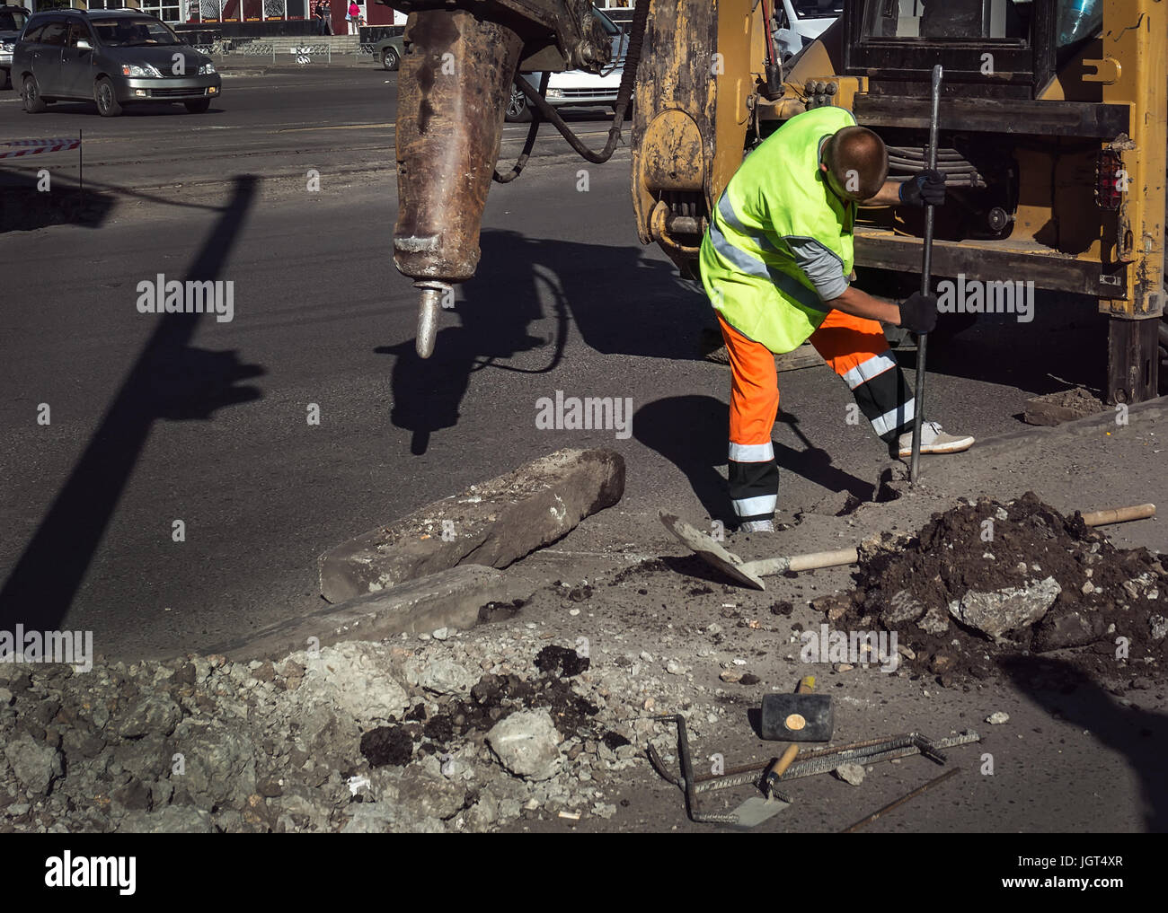 Worker repairing a road hammer crowbar asphalt next to the excavator on ...