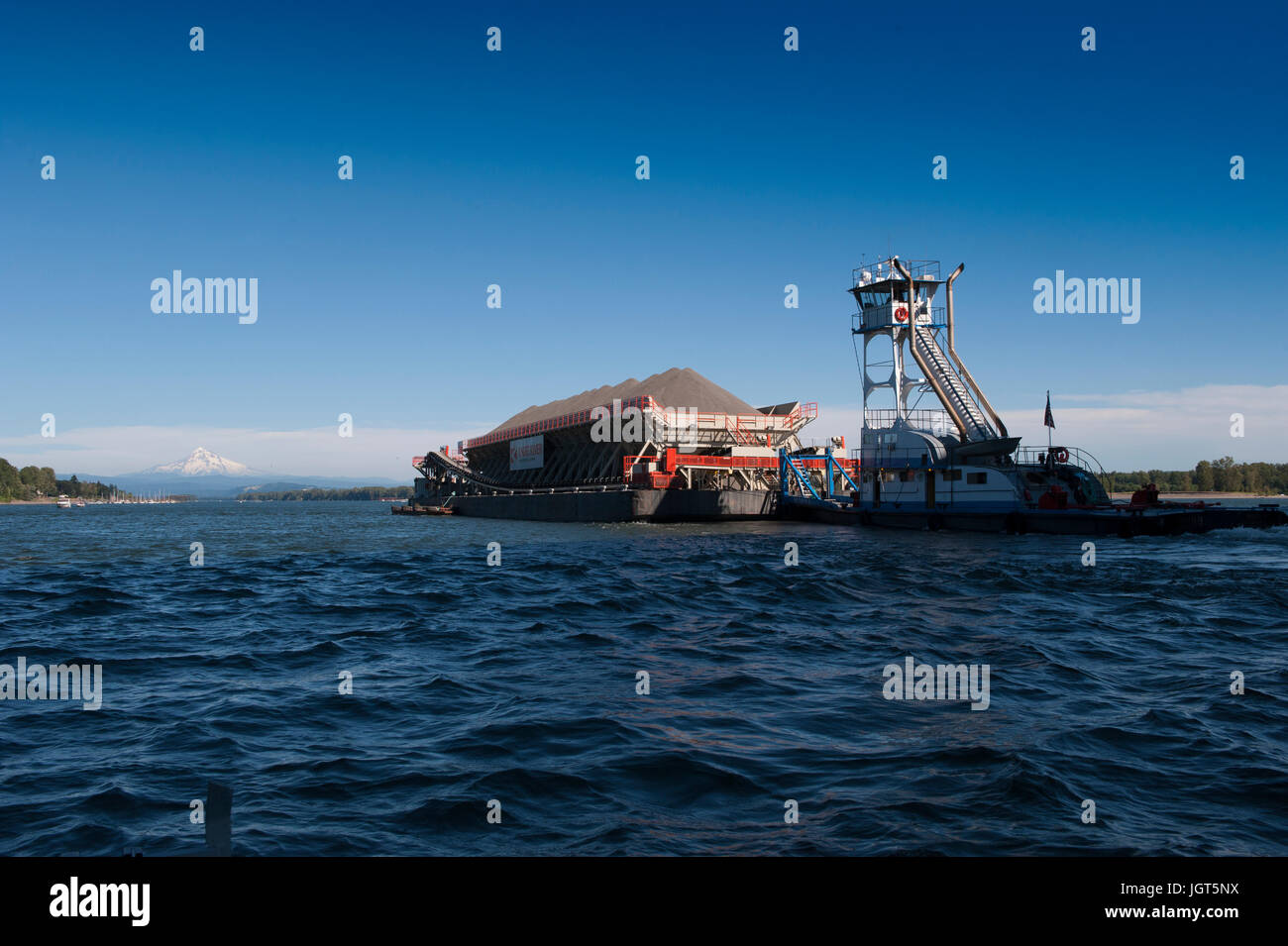 A towboat pushes an aggregate loaded barge up the Columbia River with ...