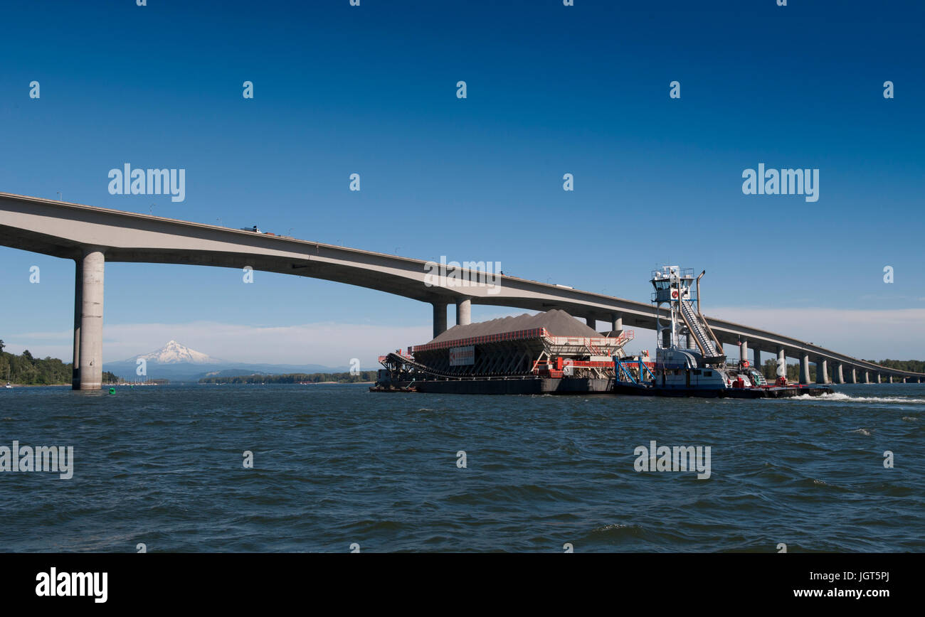 A towboat pushes an aggregate loaded barge up the Columbia River with ...