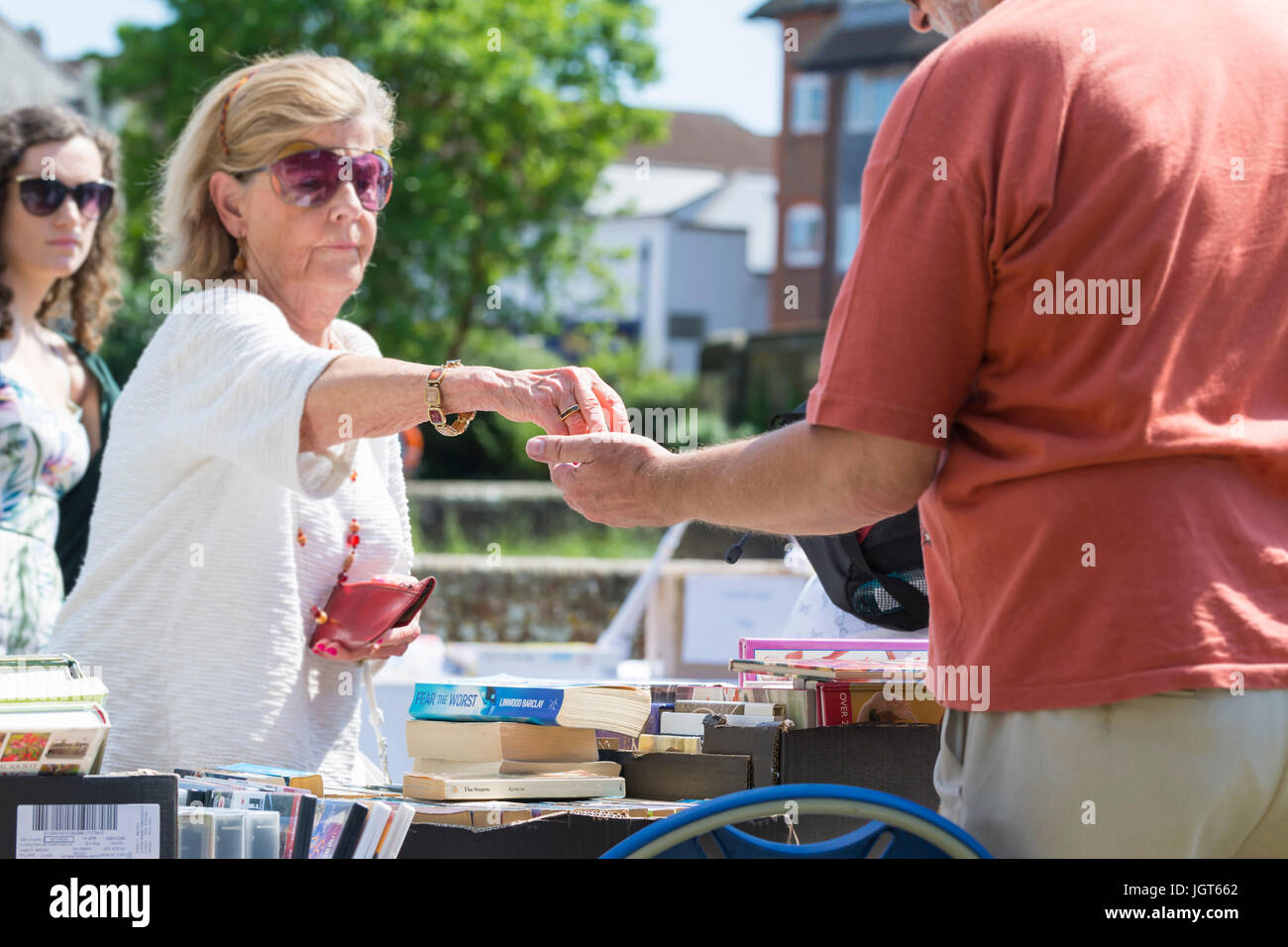 Woman paying for goods at an outdoor market stall with cash Stock Photo ...