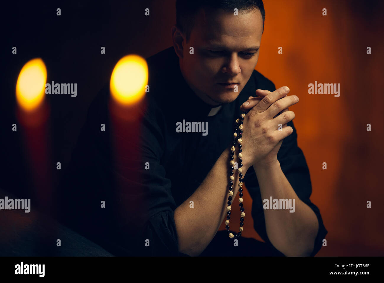 Young Catholic Praying priest. Portrait of priest Next to the candles ...