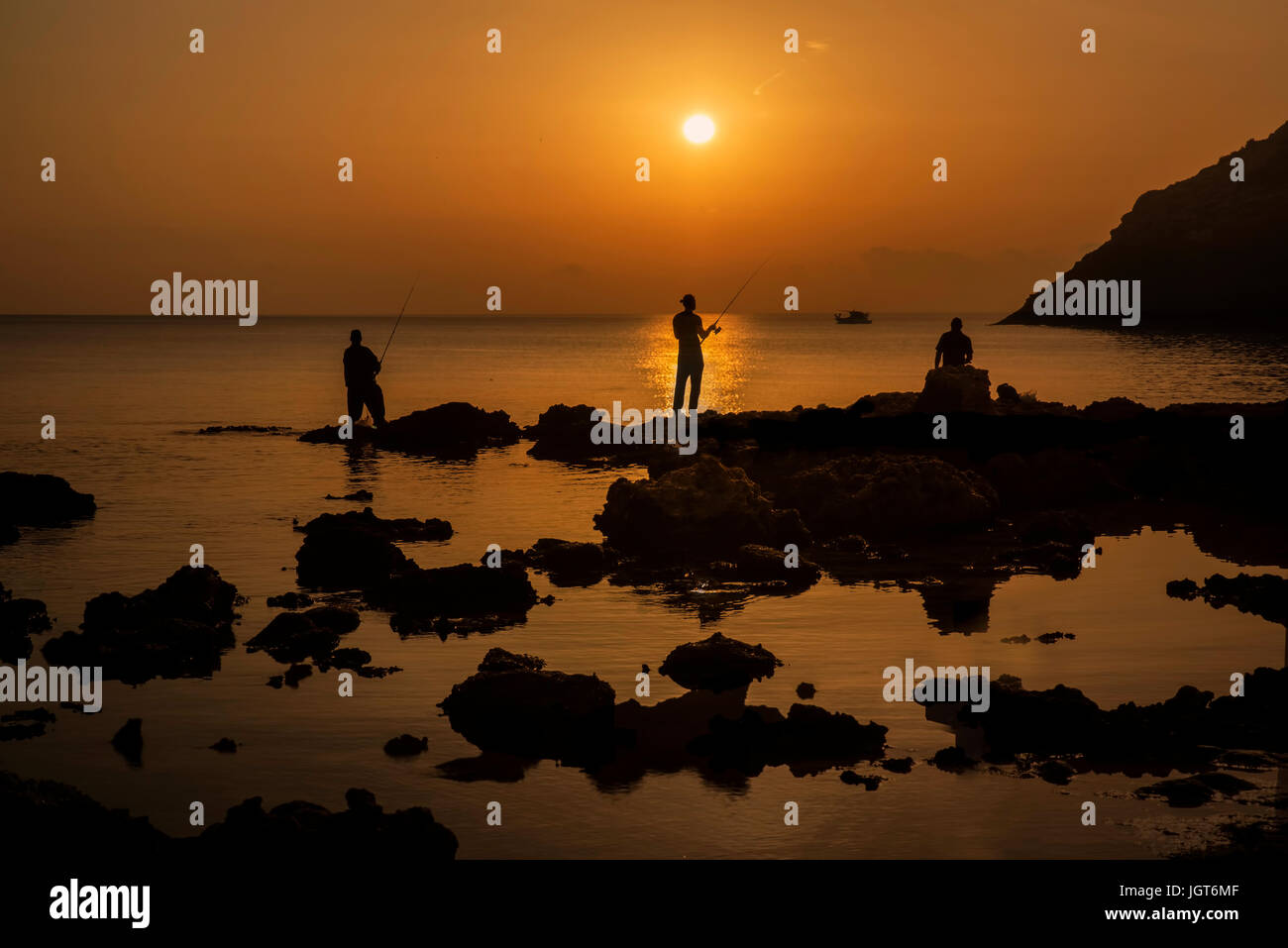 Three fishermen fishing in the ocean at sunset Stock Photo - Alamy