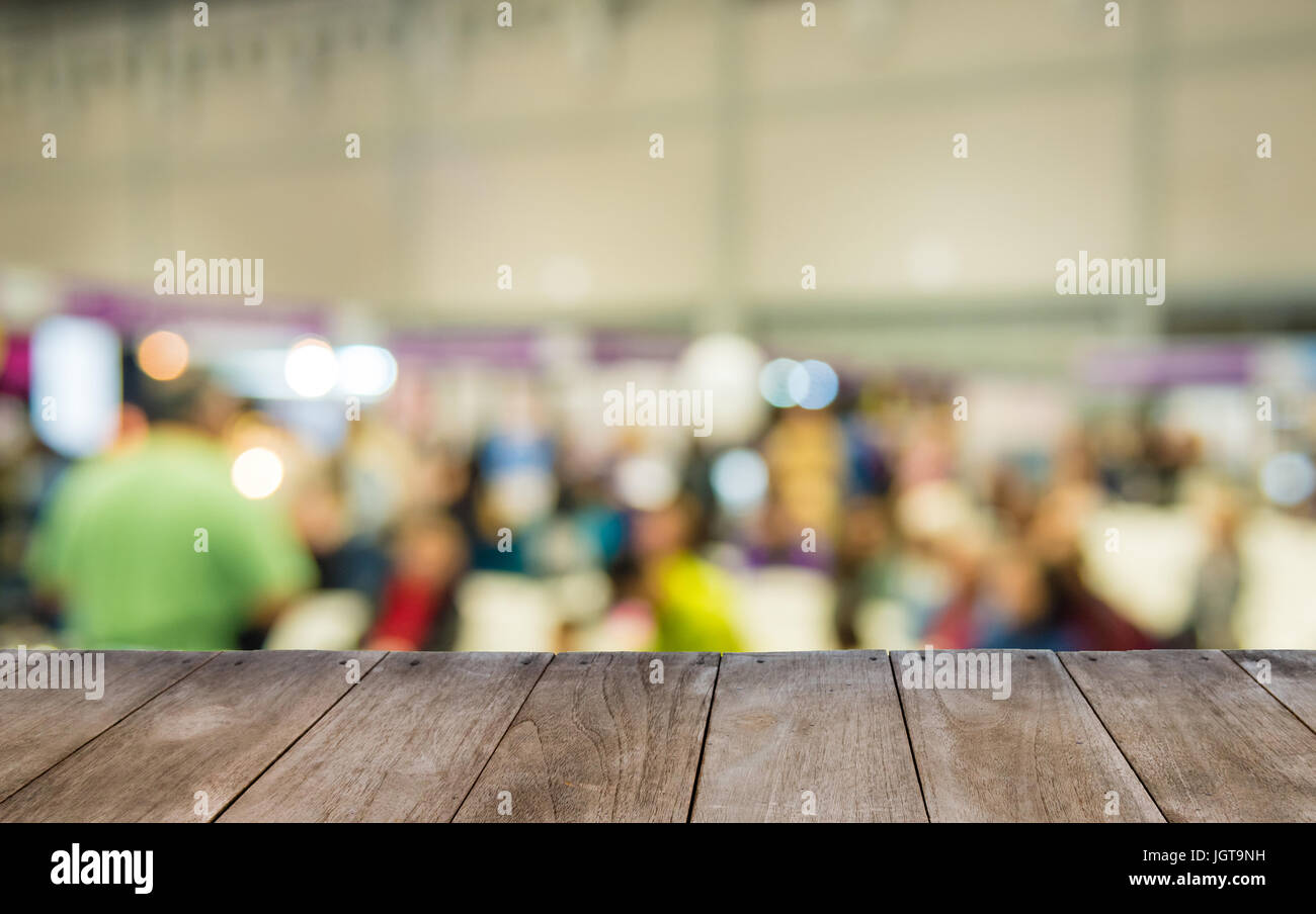 Empty wooden table in front of blurred people in auditorium at ...