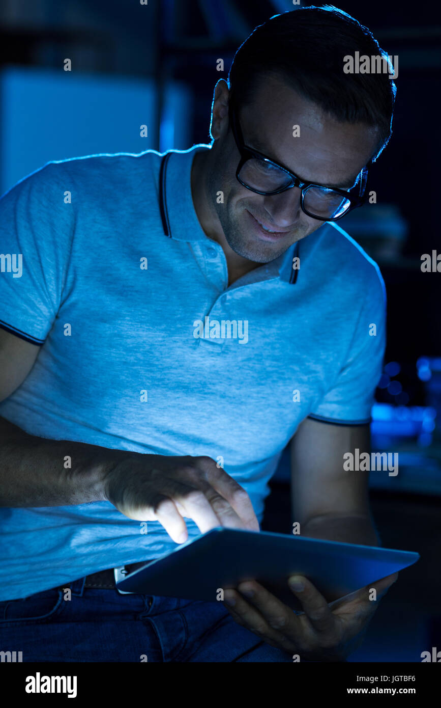 Optimistic clever man reading something on his tablet Stock Photo - Alamy