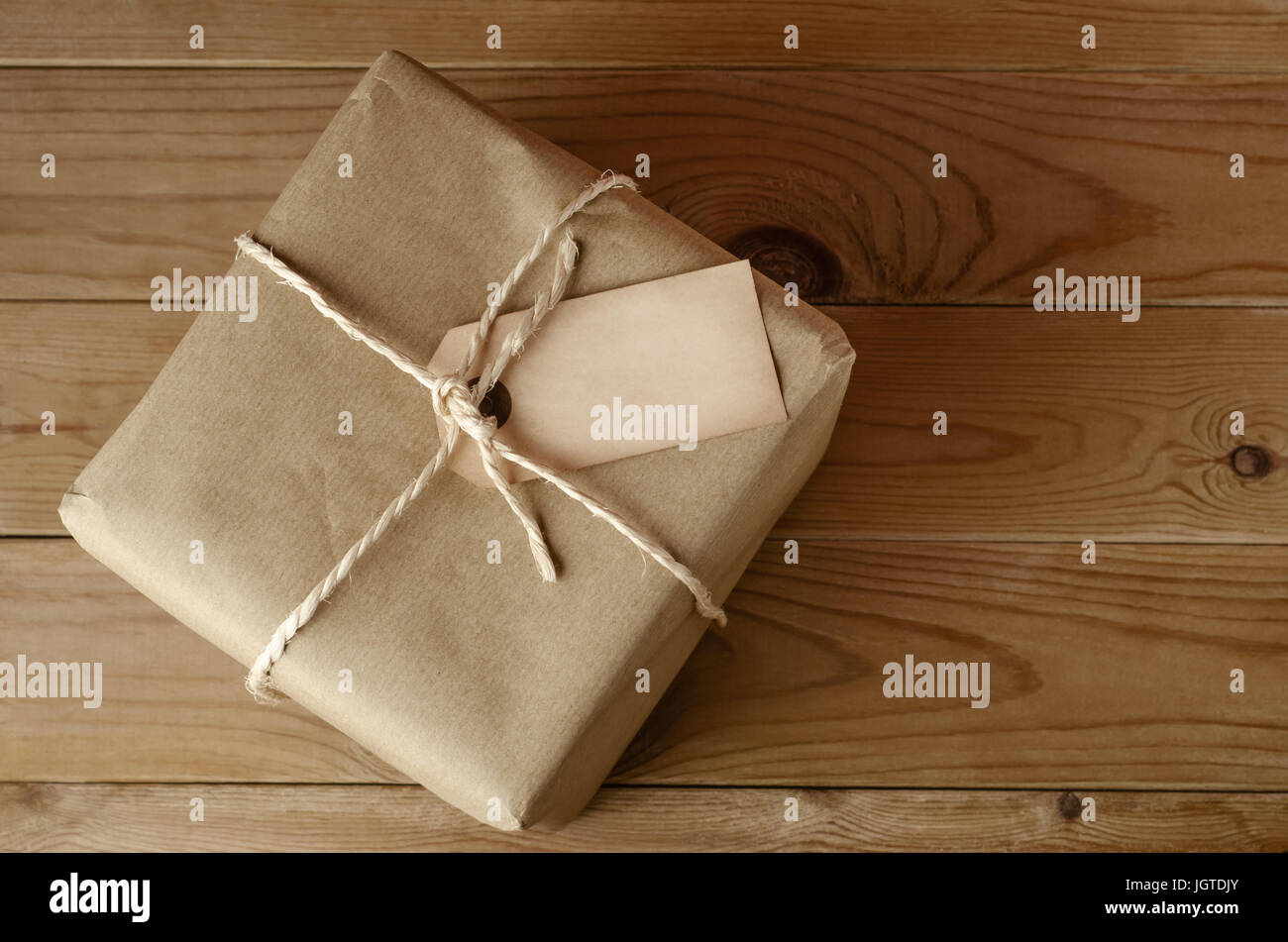 Overhead shot of a brown paper parcel, tied with string. Blank label ...