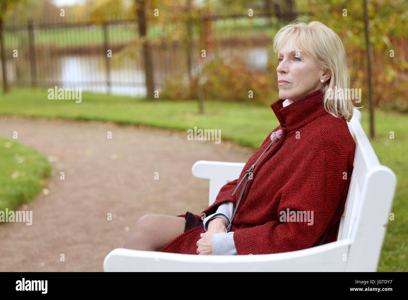 Thoughtful senior woman sitting on a bench in the park Stock Photo - Alamy