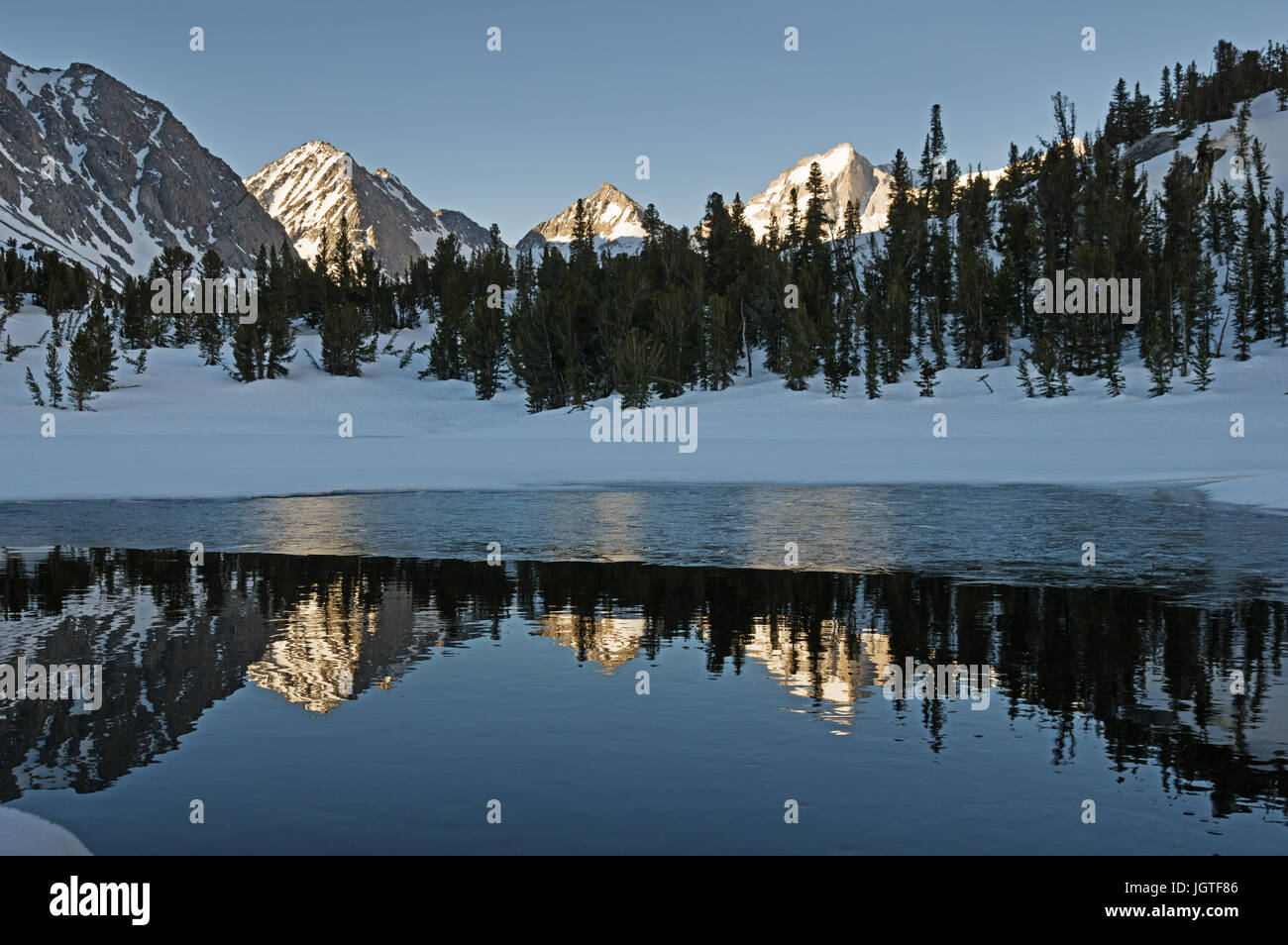 mountains reflected in a pool in a snowy pond in the Eastern Sierra ...