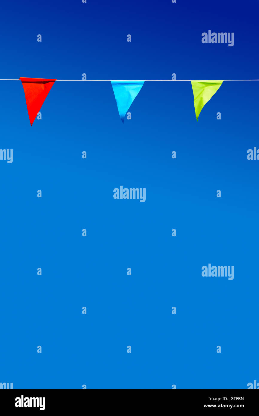 Bunting with three multicolor triangular party flags against blue sky ...