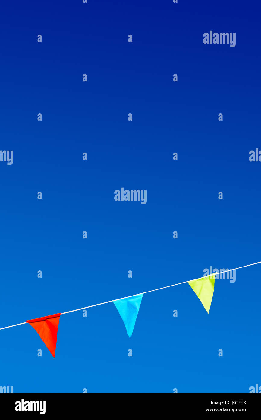 Bunting with three multicolor triangular party flags against blue sky ...