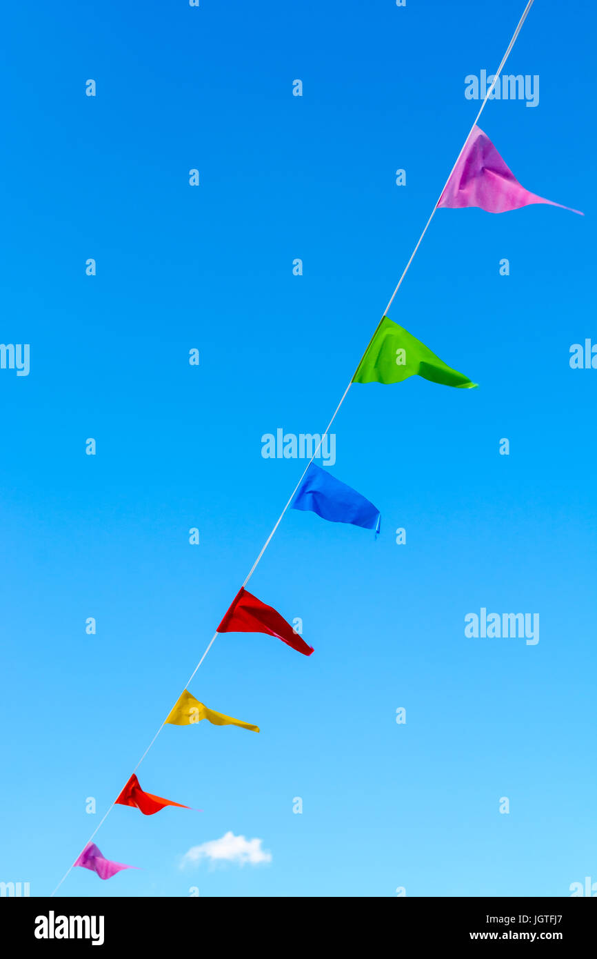 Bunting with colorful triangular party flags blowing in the wind ...