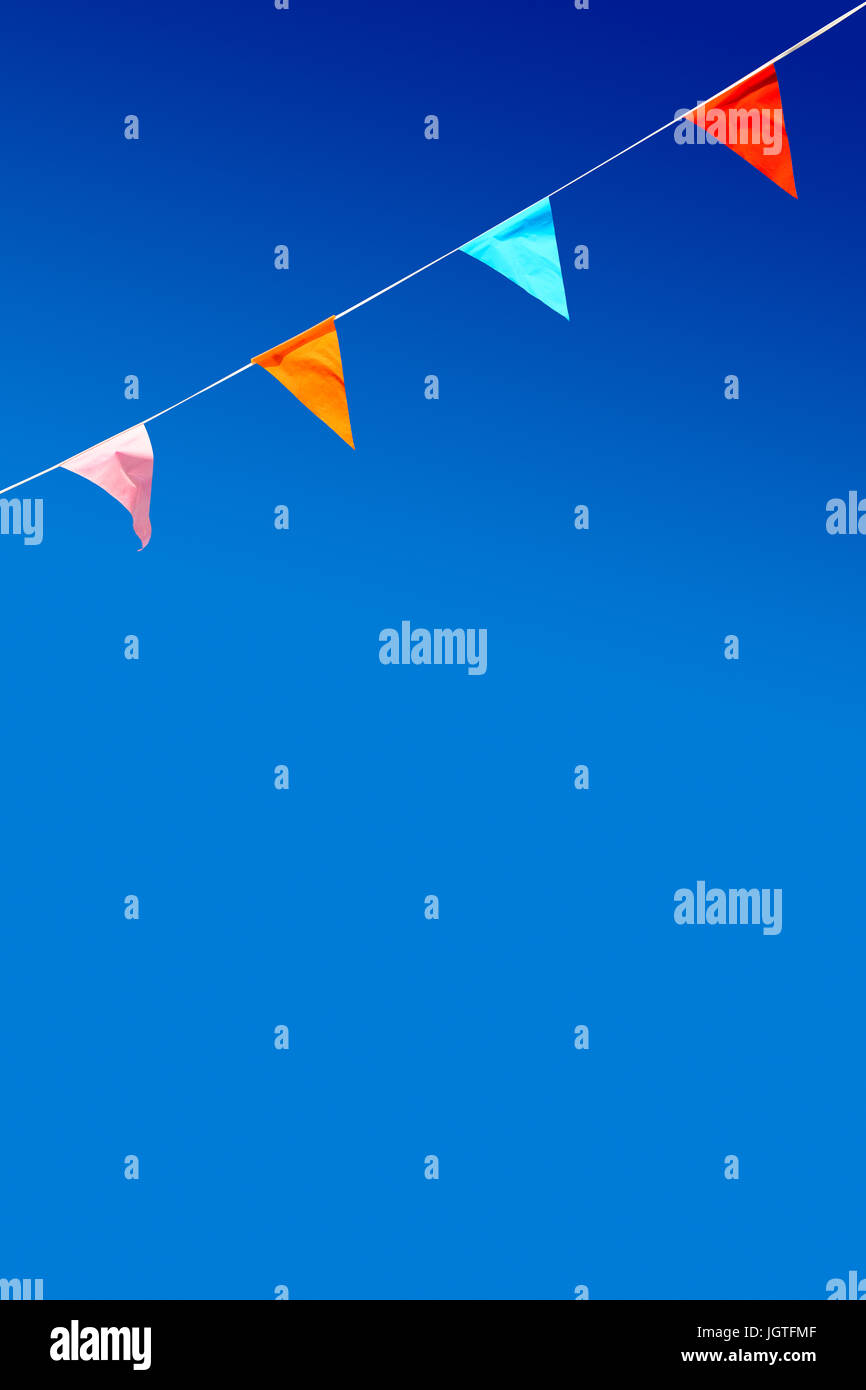 Bunting with four multicolor triangular party flags against blue sky ...