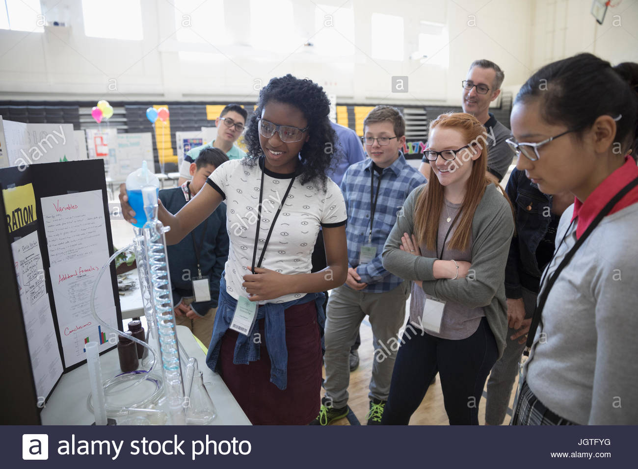 Middle school students watching scientific experiment at science fair ...