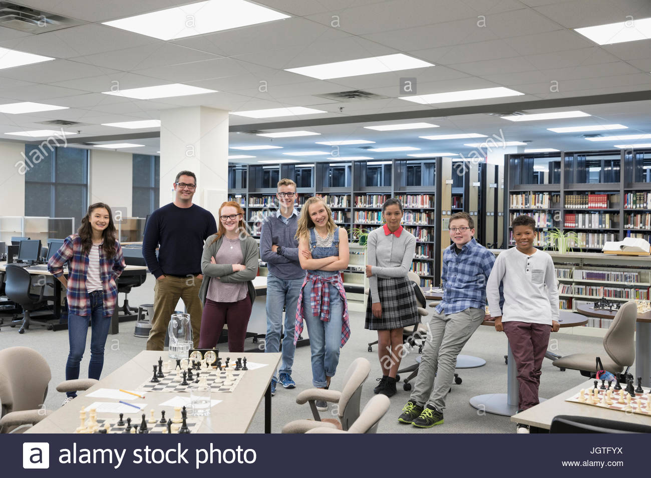 Portrait confident teacher and middle school student chess club in ...