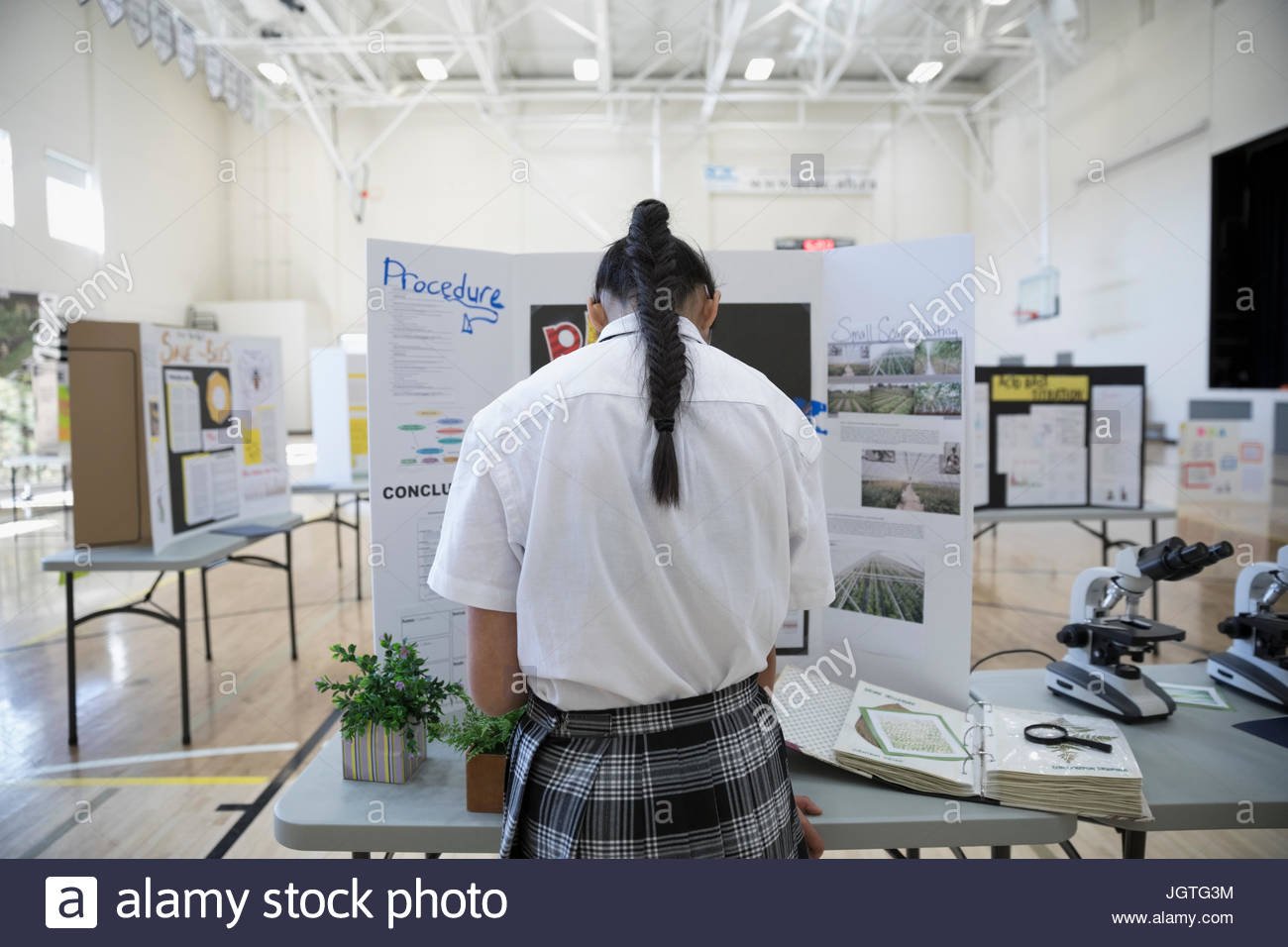 Girl middle school student viewing science project at science fair ...