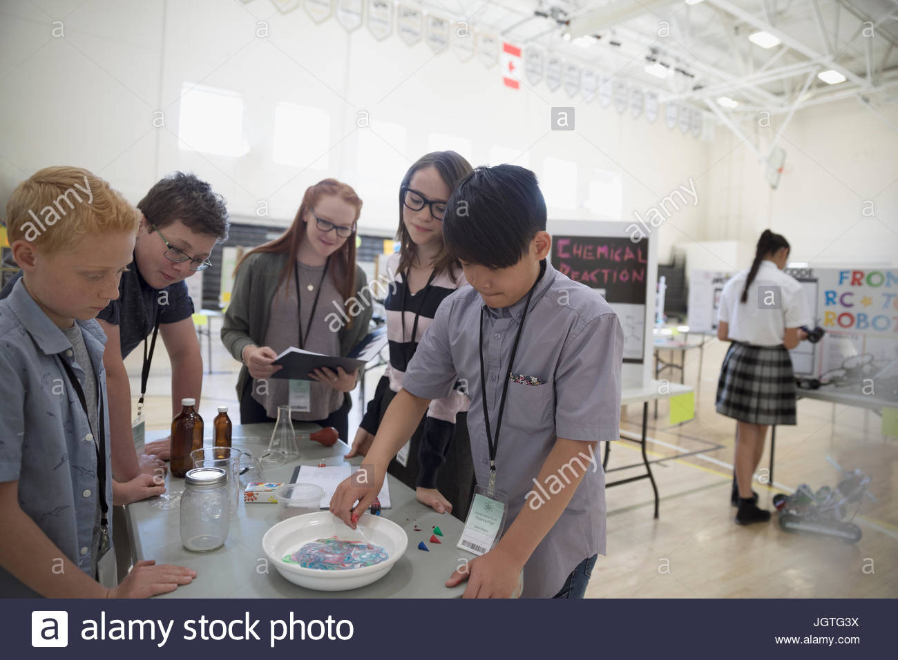 Middle school students conducting scientific experiment at science fair ...