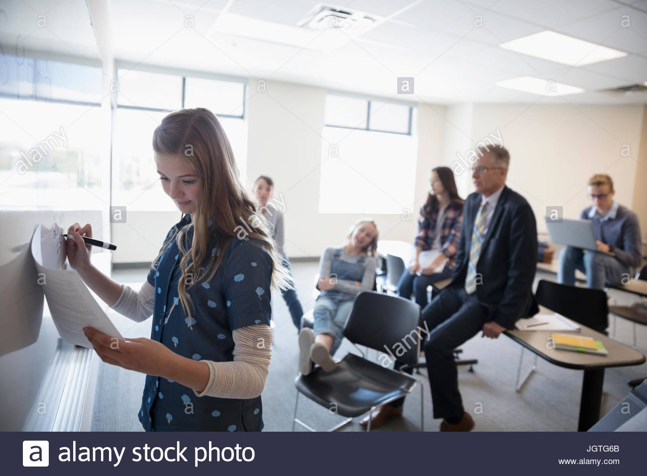 Girl middle school student writing at whiteboard in classroom Stock ...