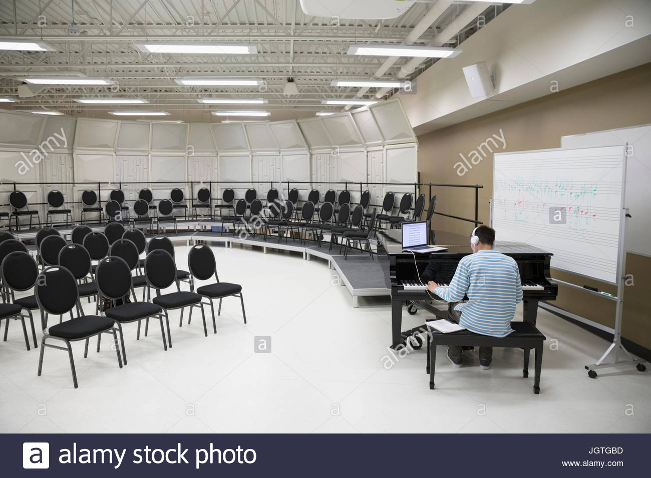 Male college student with headphones and laptop practicing piano in ...