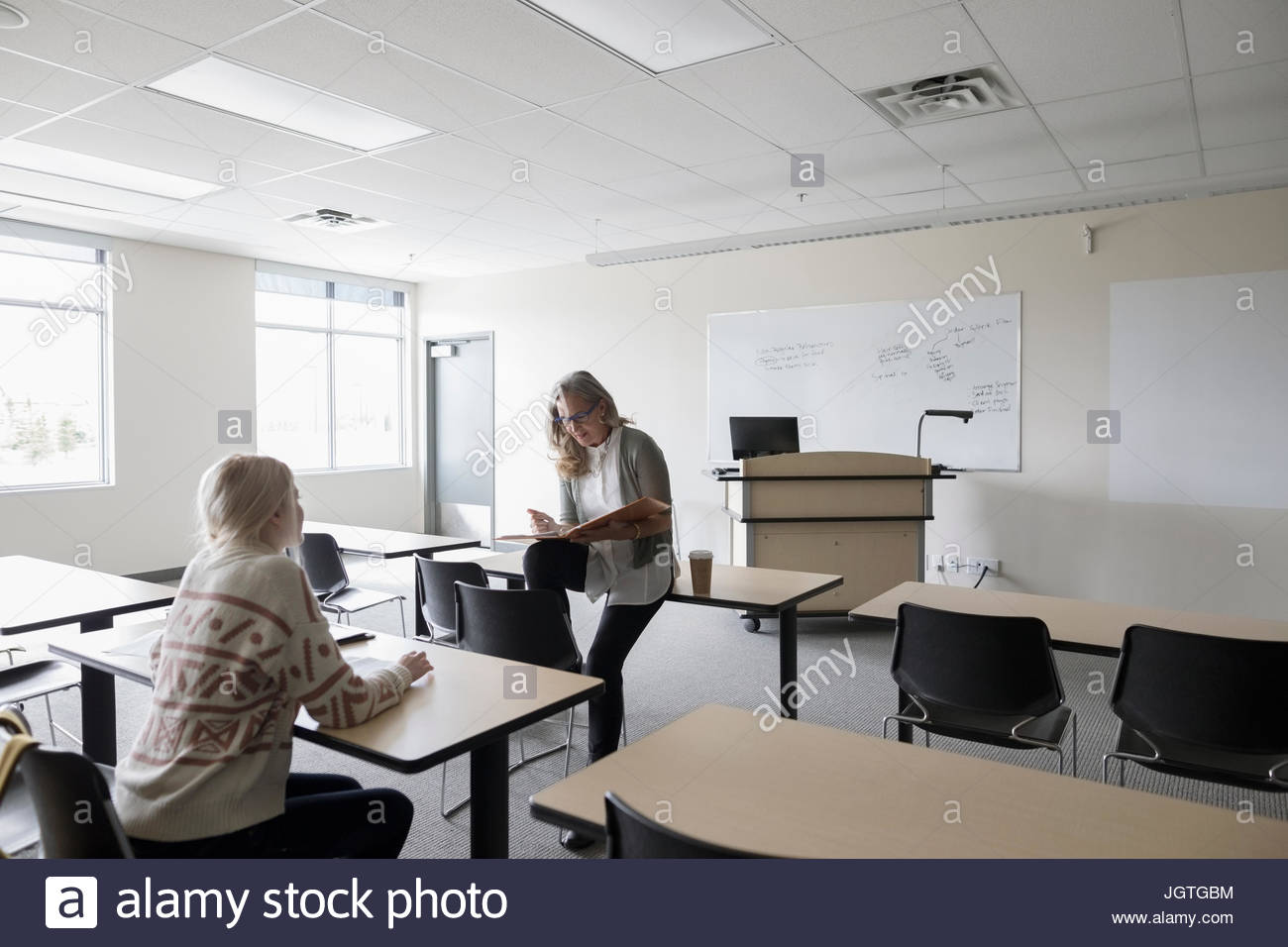 Female college professor and student talking in classroom Stock Photo ...