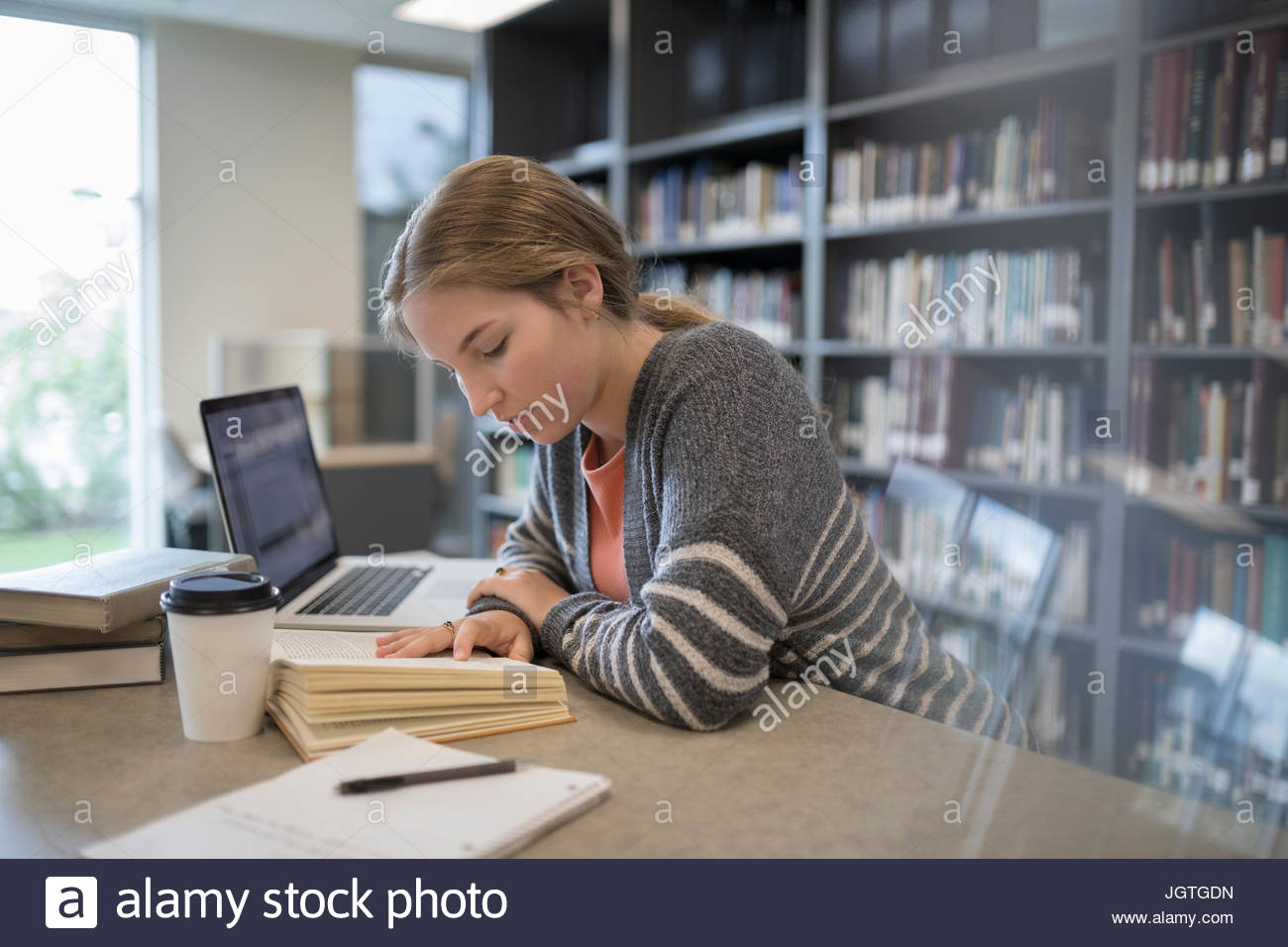 Focused female college student studying, reading book in library Stock ...