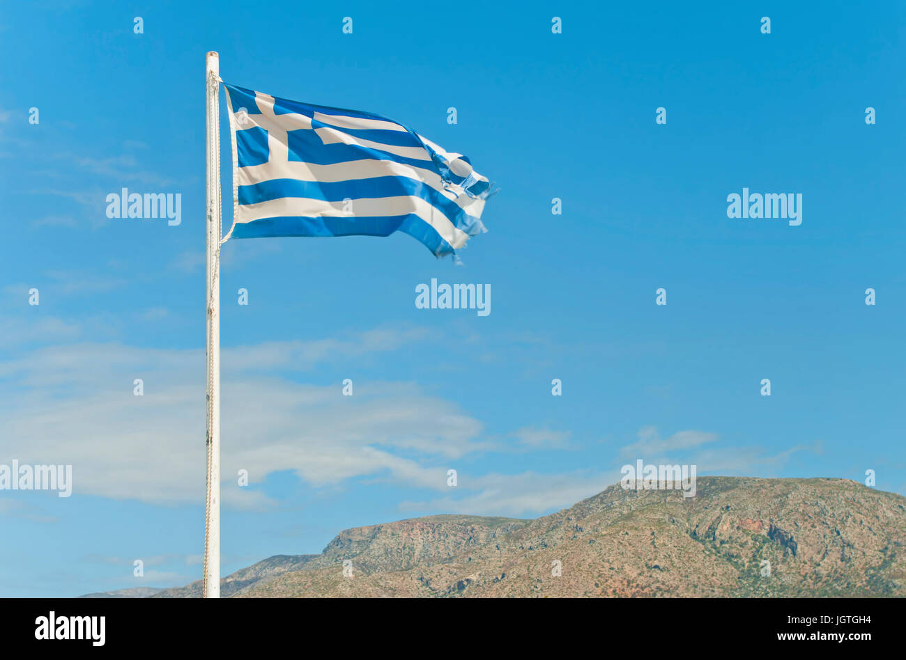 old torn Greek flag waving on old rusty flag-post on sunny day with ...