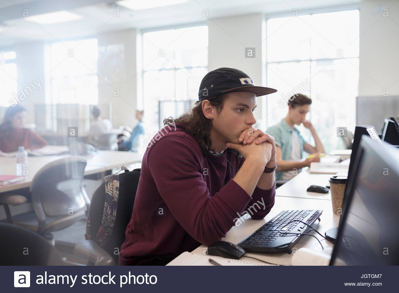 Serious male college student studying, researching at computer in ...