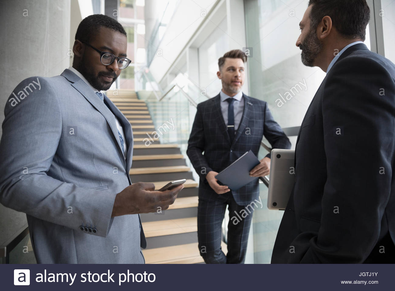 Businessman checking cell phone on office stairs Stock Photo - Alamy