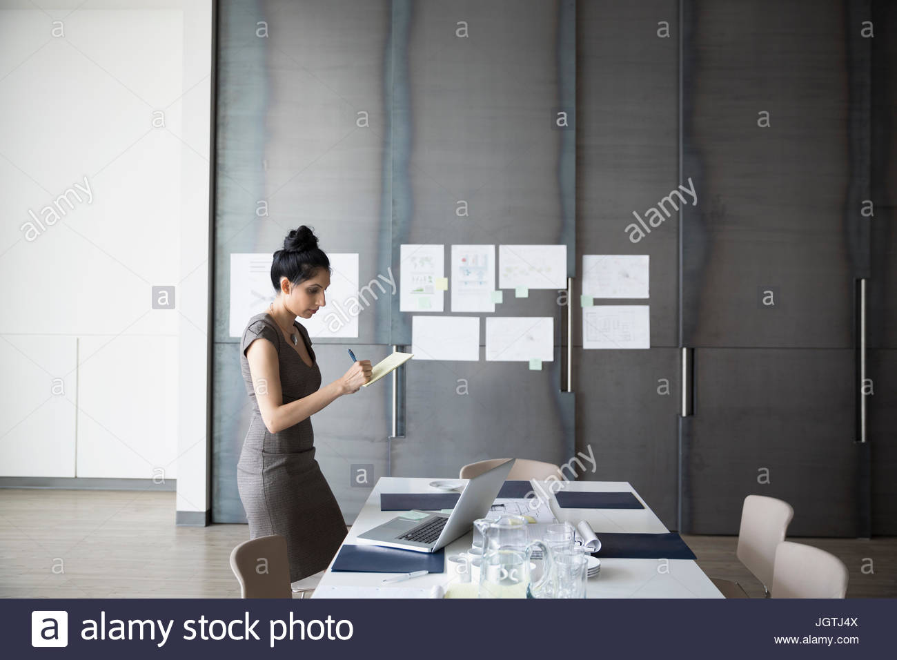 Businesswoman taking notes, preparing for meeting in conference room ...
