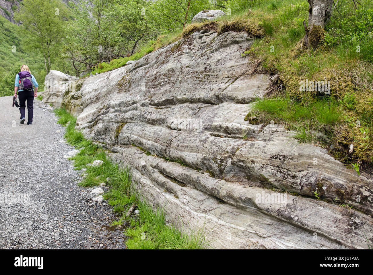 Tourist on trail path by horizontal scratch lines gauged in rock by ...