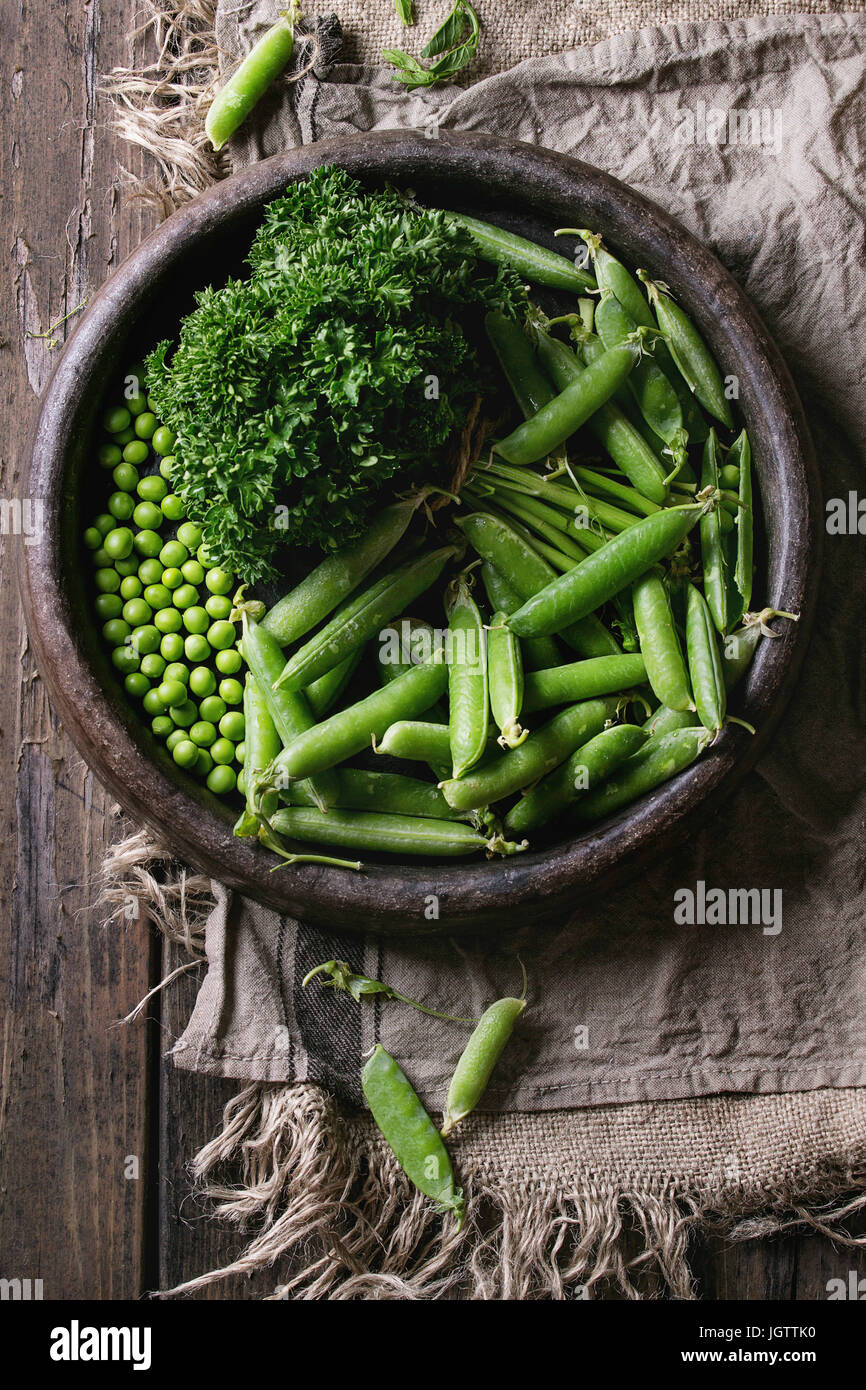 Young organic green pea pods and peas in terracotta tray and bundle of ...